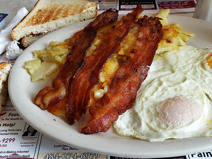 The breakfast trinity: perfectly cooked eggs, crispy bacon, and home fries that somehow manage to be both crispy and tender. Morning salvation on a plate.