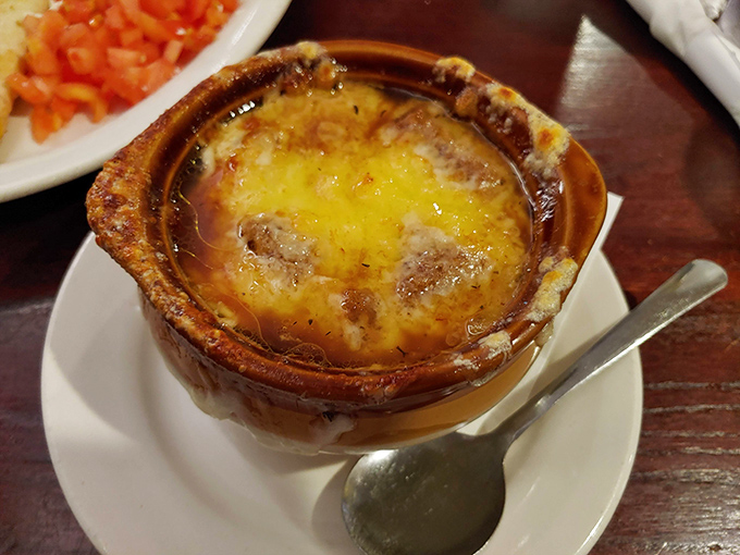 Steam rises from this crock of French onion soup like a savory fog, the melted cheese ceiling requiring the satisfying breach that only your spoon can provide.