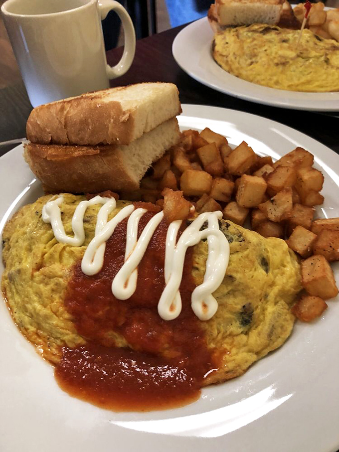 This omelet wears its salsa and sour cream like a fashionable scarf. Golden exterior, fluffy interior, and home fries that could start their own fan club.