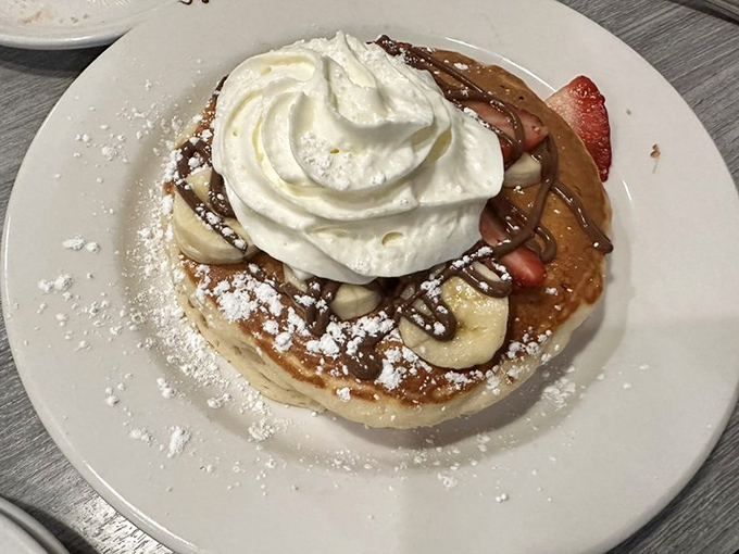 These pancakes, adorned with fresh fruit, whipped cream, and powdered sugar, aren't just breakfast—they're an edible work of art worth waking up for.