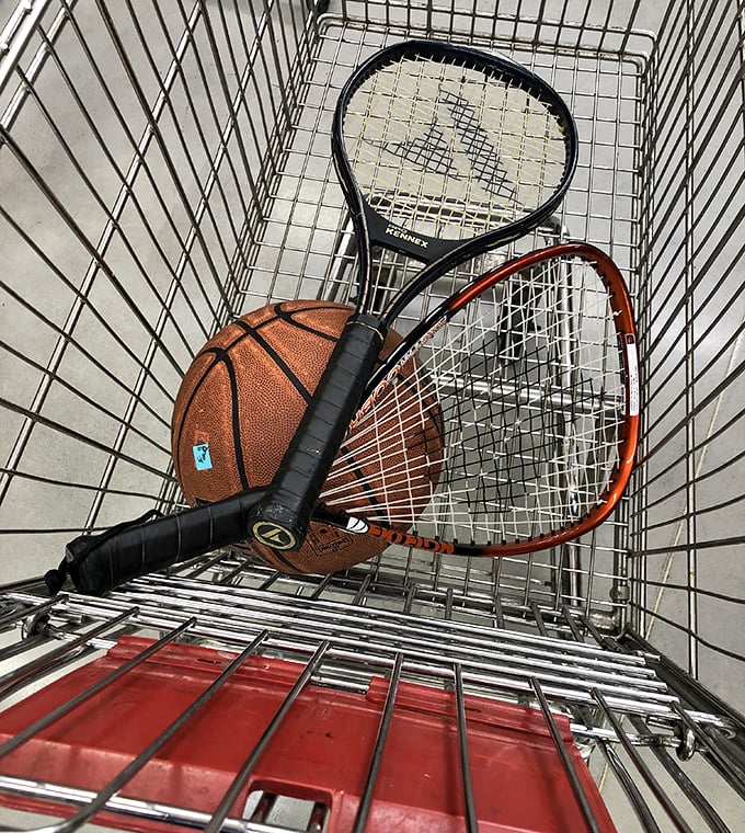 A shopping cart holding life's recreational possibilities. That basketball and tennis racket combo screams "optimistic weekend plans."