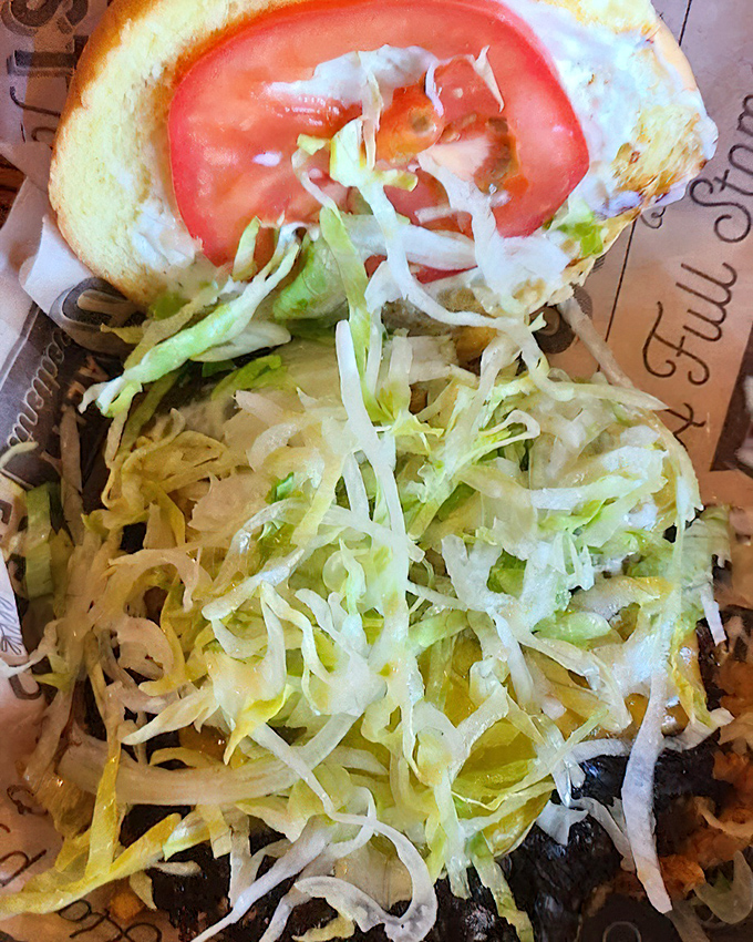 Fresh lettuce and tomato add a crisp counterpoint to the deeply caramelized patty—a textural symphony in every bite.