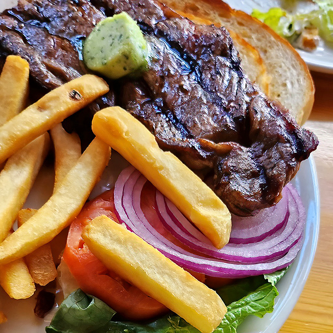 A steak sandwich that means business, with fries standing at attention and vegetables adding a pop of color to the proceedings.