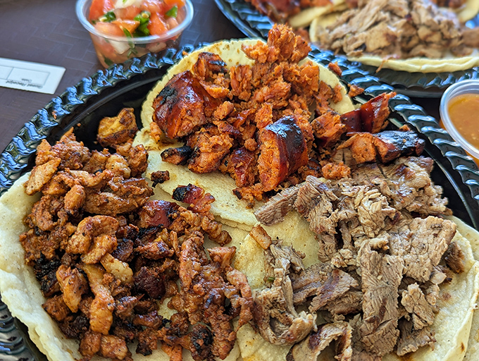 The holy trinity of tacos: different meats, same promise of transportive flavor that makes you forget you're eating off a plastic plate.