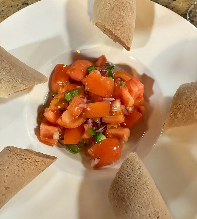 Tomato Fitfit surrounded by injera&mdash;a refreshing salad that proves Ethiopia mastered the "deconstructed" concept long before it became trendy in American restaurants.