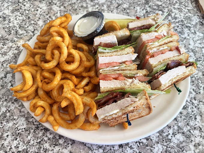 The legendary club sandwich arrives with curly fries&mdash;architectural perfection between bread slices that would make Frank Lloyd Wright jealous.