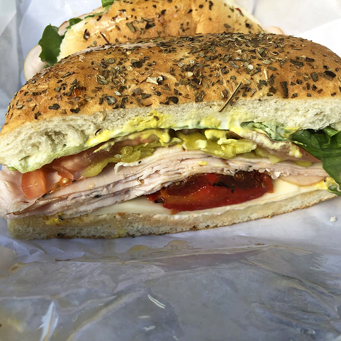 A sandwich so perfectly constructed it deserves its own blueprint. The herb-flecked bread cradles layers of meat with architectural precision.