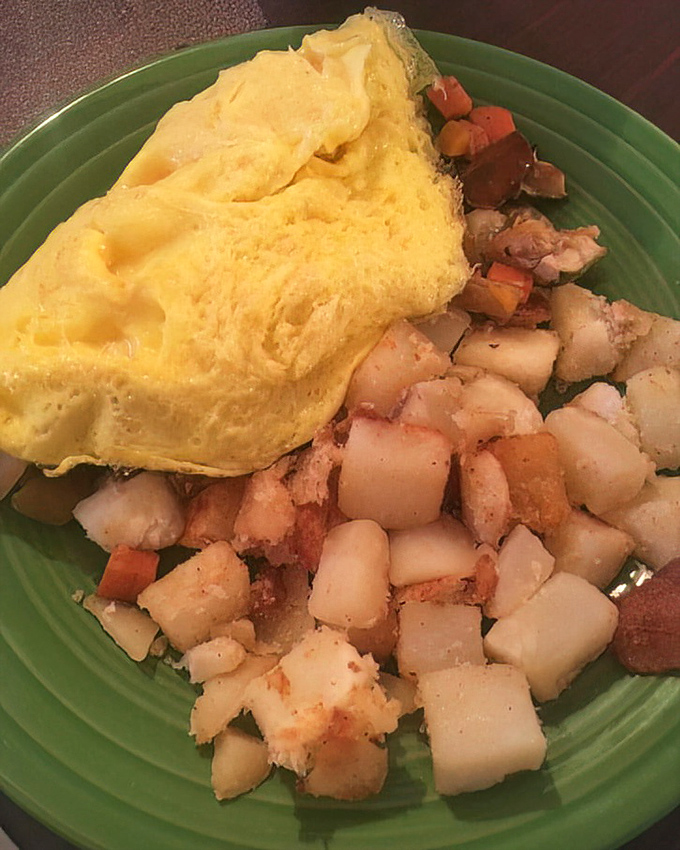 A veggie omelet that transforms humble ingredients into morning magnificence, paired with perfectly seasoned home fries.