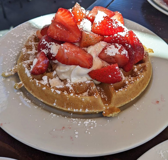 This waffle isn't just wearing strawberries&mdash;it's flaunting them. The powdered sugar snowfall completes a breakfast that's basically acceptable dessert.