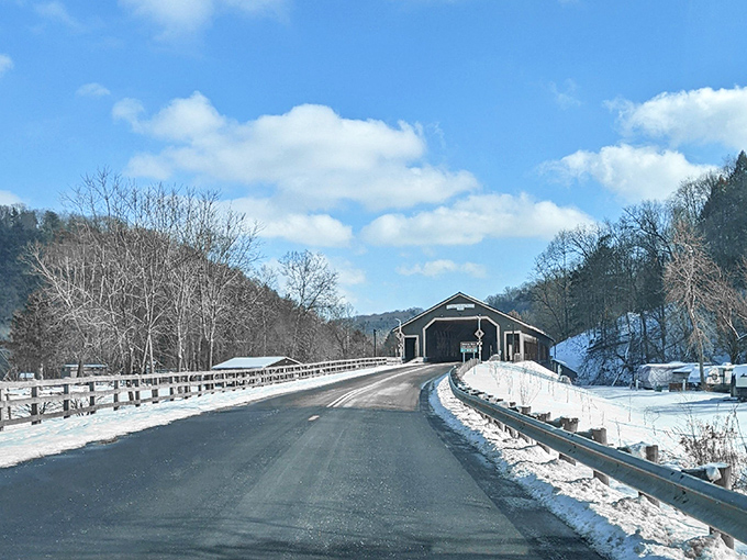 Winter transforms the byway into a serene wonderland, with the covered bridge standing like a cozy cabin beckoning travelers through the snow.