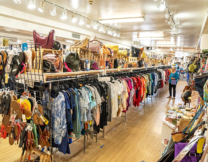 The women's clothing section stretches into the distance like a fashionista's dream, with handbags perched above like colorful sentinels guarding the treasures below.