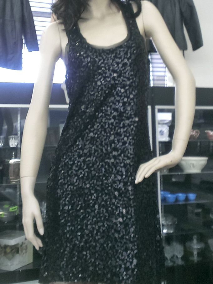 A sequined dress on a mannequin stands sentinel, silently asking, "Don't you have an occasion coming up that needs a little extra sparkle?"