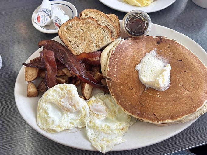 The holy trinity of breakfast: golden pancakes, perfectly cooked eggs, and bacon that's achieved that magical balance between crisp and chewy.