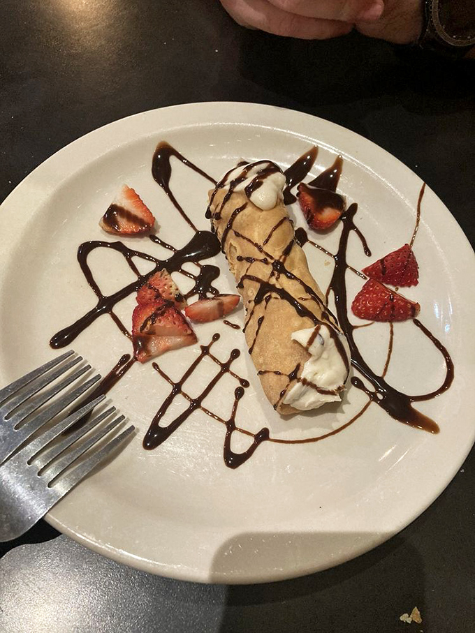 This cannoli isn't just dessert; it's the final act in an Italian opera, complete with chocolate drizzle and strawberry supporting players.
