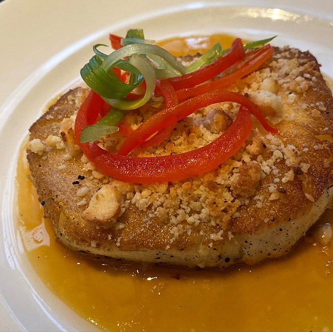 The Chilean sea bass sits in a golden pool of sauce, topped with a crown of peppers like jewelry for your dinner.