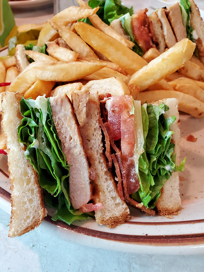 The club sandwich&mdash;a skyscraper of flavor requiring structural engineering skills to eat. Those crisp fries aren't sidekicks; they're co-stars in this lunch drama.