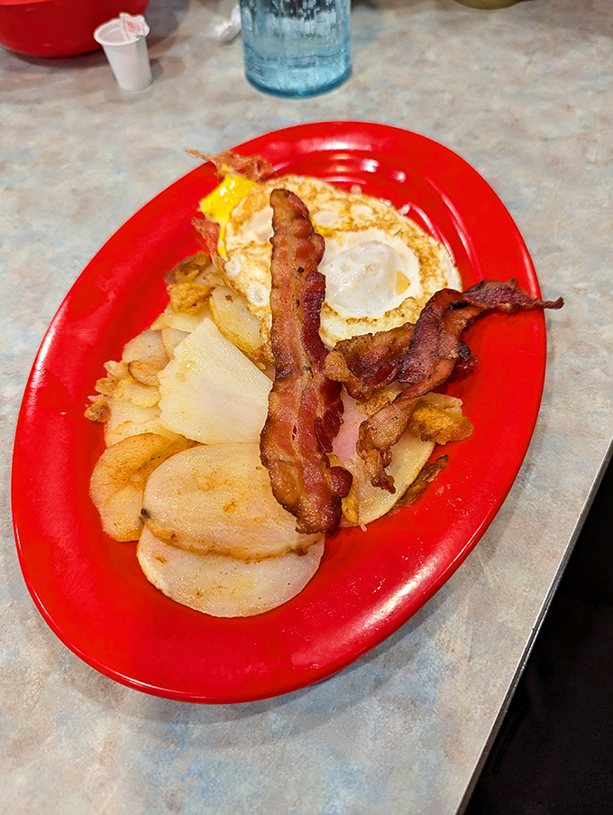 The breakfast trinity: perfectly crisp bacon, golden home fries, and eggs with yolks ready to create their own sunshine.
