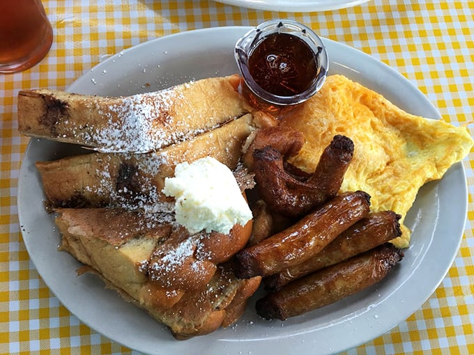 The breakfast trinity: golden French toast dusted with powdered sugar, eggs that know their purpose, and sausage links with perfect snap.