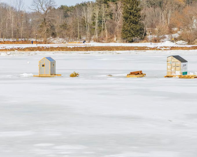 Ice fishing huts dot the frozen Squamscott River like miniature homesteads, a winter tradition where patience is measured in hours and success in inches.