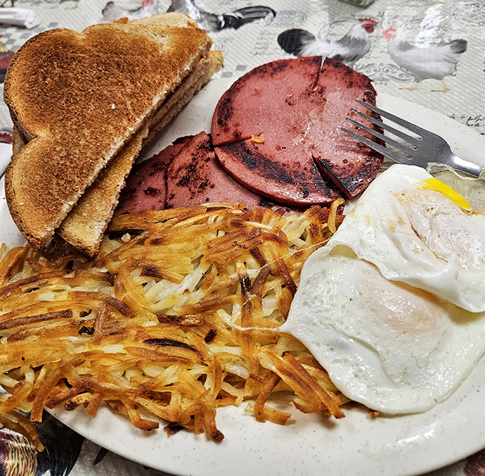 The breakfast trinity: perfectly grilled ham, crispy hash browns, and eggs that sunny side up your entire day.