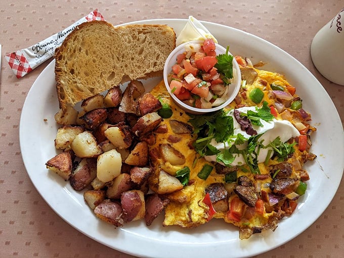 An omelet that refuses to be ignored, accompanied by potatoes that have achieved the perfect crisp-to-tender ratio&mdash;breakfast engineering at its finest.