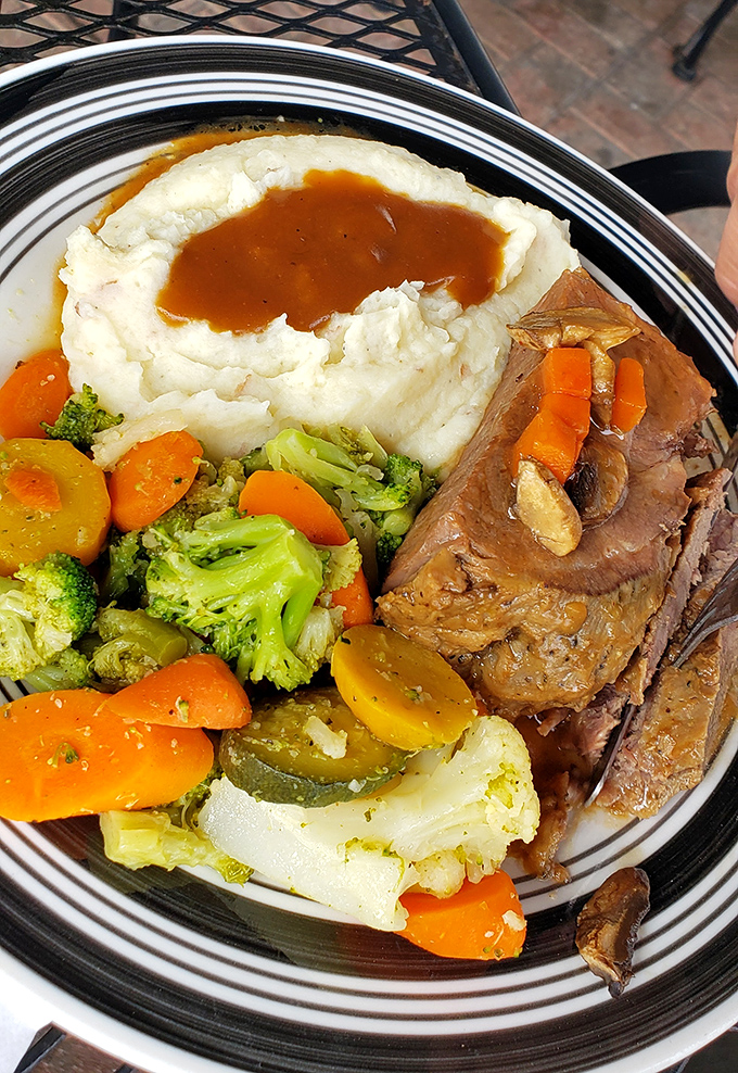 The star of the show: mashed potatoes with gravy creating a perfect volcano crater, surrounded by tender meat and vibrant vegetables.