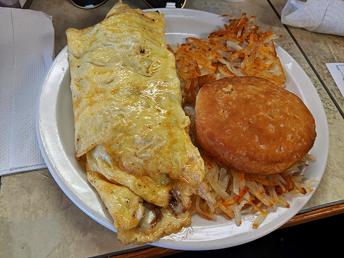 The holy trinity of breakfast perfection: a fluffy omelet, crispy-edged hashbrowns, and a biscuit that's clearly not taking orders from any diet plan.