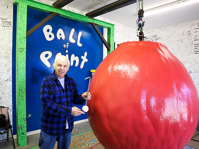 The caretaker poses with his chromatic creation, looking like a proud parent at a particularly unusual graduation ceremony.