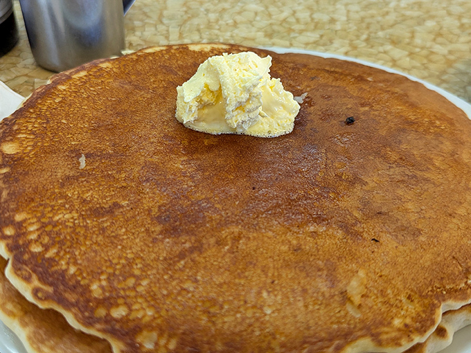A pancake so perfectly golden it deserves its own spotlight. That pat of butter slowly melting into breakfast nirvana is pure morning poetry.