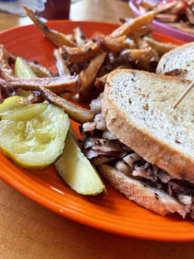 This pastrami sandwich stands taller than most toddlers and packs more flavor than a Broadway musical finale.