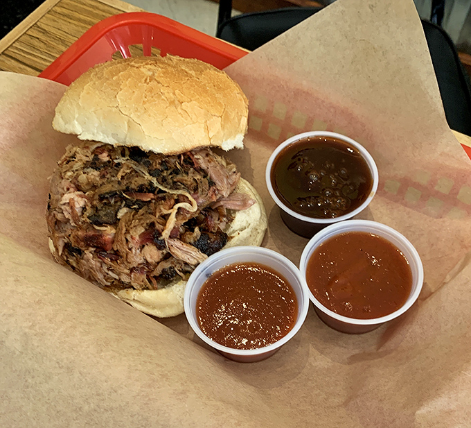 A pulled pork sandwich that doesn't need fancy dress-up to impress, just honest smoke and three sauce options standing by like loyal friends.