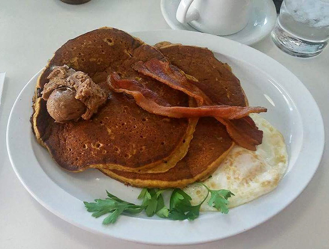 Pumpkin pancakes that capture autumn in every bite, topped with bacon strips and a sunny-side smile.