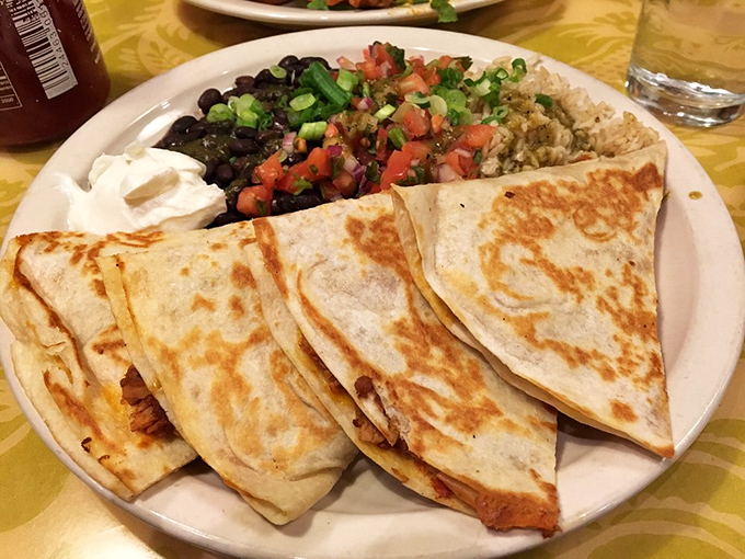 Quesadillas so perfectly crisped they make that satisfying crackle when cut, served alongside rice and beans that refuse to be mere supporting actors.