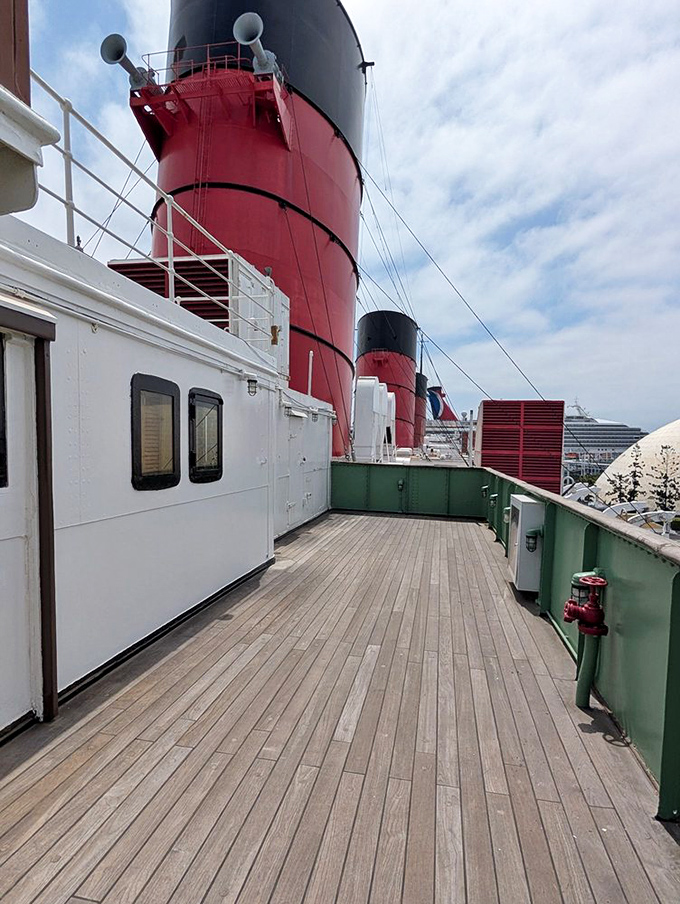 Walking these wooden decks beneath the iconic red funnels feels like strolling through a maritime museum where every plank has a story to tell.