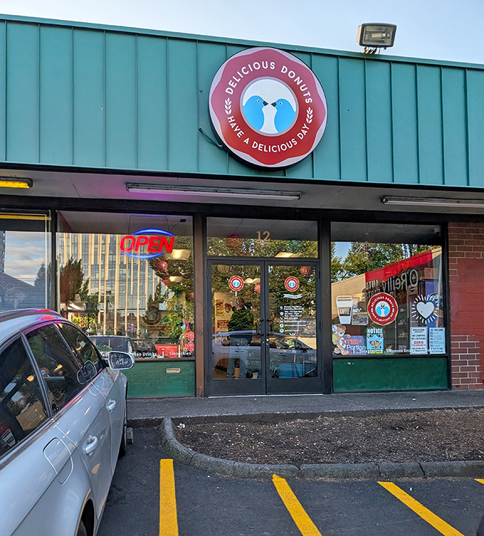 Delicious Donuts' storefront features a distinctive logo with two blue birds facing each other. The simple green exterior hides Portland's beloved donut destination.