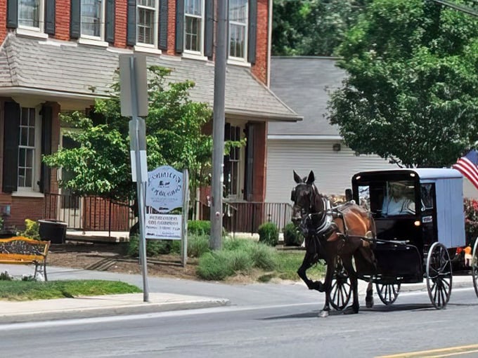 Horse and buggy passing the brick buildings of Intercourse&mdash;where transportation remains unhurried and patriotism flies on a small but proud flag.