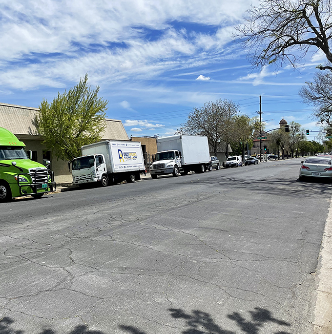 Downtown Modesto feels lively and welcoming, with trucks and cars lining the street, spring trees blooming, and the blue California sky above.