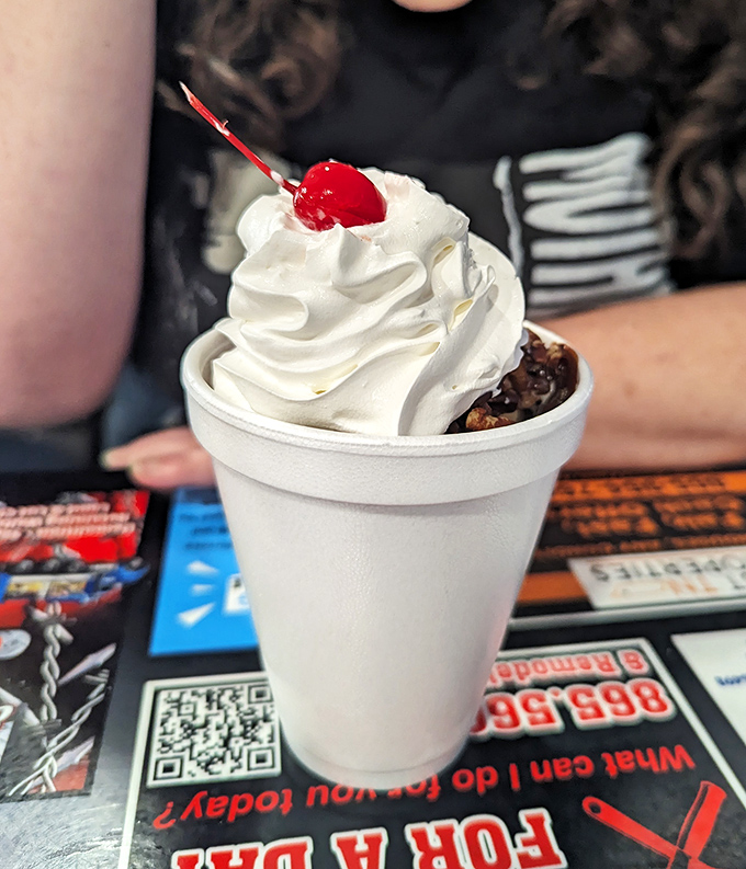 A mountain of whipped cream with a cherry sentinel standing guard over hidden ice cream treasures. Spoon required, restraint optional.