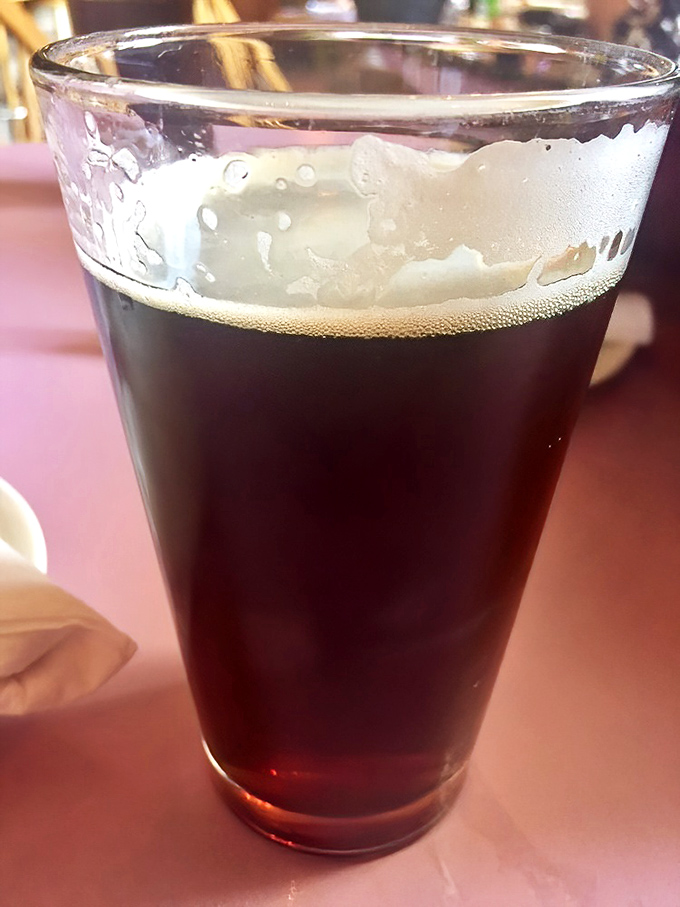A perfectly poured dark beer with that ideal foam crown—because sometimes the best dining companion doesn't talk back.