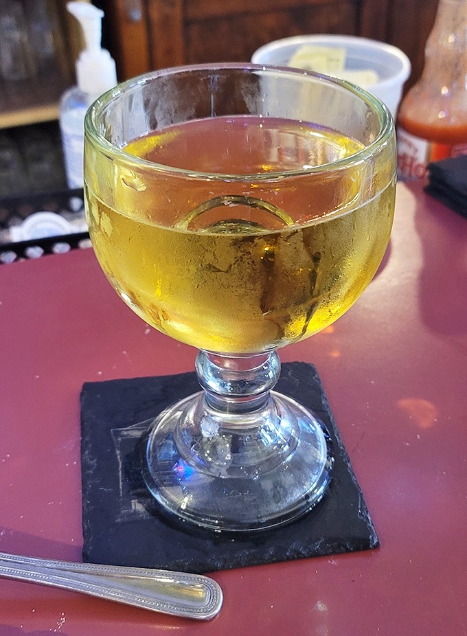 A goblet of golden beer sits regally on its slate throne, promising refreshment that pairs perfectly with everything from brain sandwiches to fried chicken.
