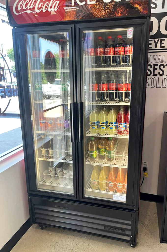 The drink cooler stands ready to extinguish the fire of spicy cheesesteaks, offering cold comfort in bottled form for parched patrons.
