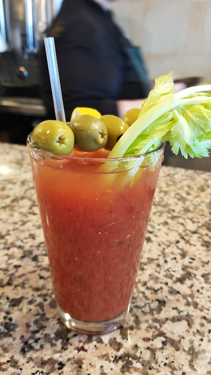The Bloody Mary arrives dressed to impress, garnished with enough olives to start your own Mediterranean vacation.