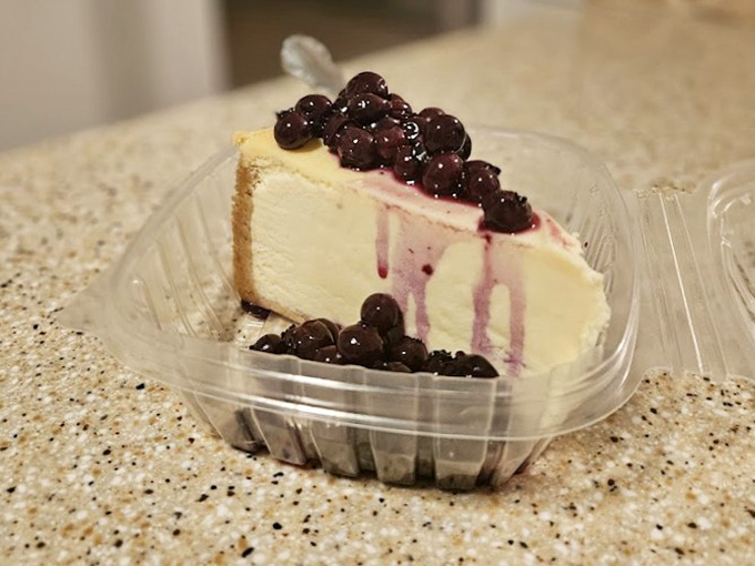 Cheesecake crowned with blueberry royalty&mdash;where New York tradition meets Florida's sweet tooth in a plastic container of pure joy.