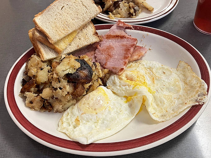 The breakfast trinity: perfectly cooked eggs, crispy-edged ham, and hashbrowns with the ideal balance of crispy exterior and tender interior. Morning salvation on a plate.