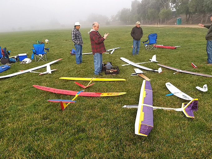 Morning fog creates a magical backdrop for these model airplane enthusiasts, proving that grown men with flying toys are having more fun than the rest of us.