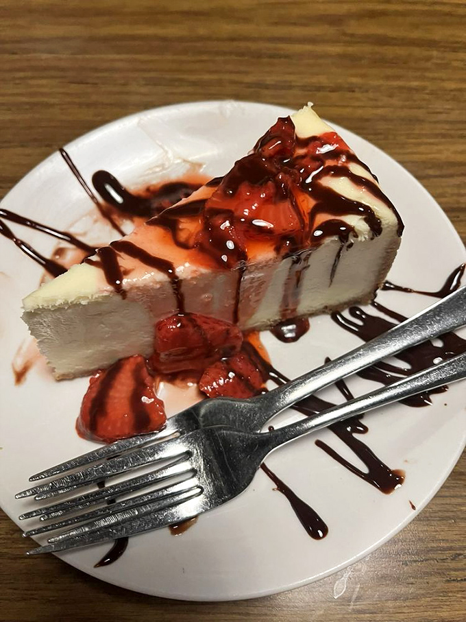 Cheesecake that makes you want to skip dinner entirely, crowned with strawberries and chocolate drizzles that zigzag like edible autographs.
