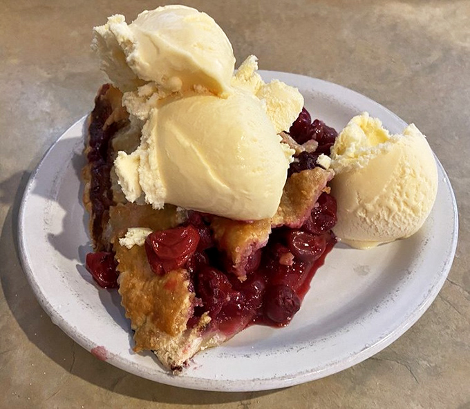 Cherry pie topped with ice cream that's melting with excitement to meet its fruity soulmate below.