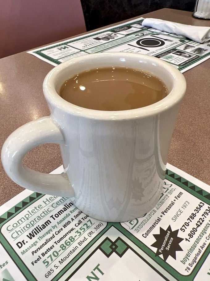 The sturdy white mug &ndash; diner coffee's natural habitat &ndash; promising warmth, caffeine, and unlimited refills for road-weary travelers.