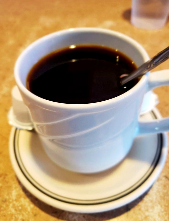 The coffee comes in that iconic white diner mug—the vessel that has launched a thousand conversations and solved countless morning grumpies.