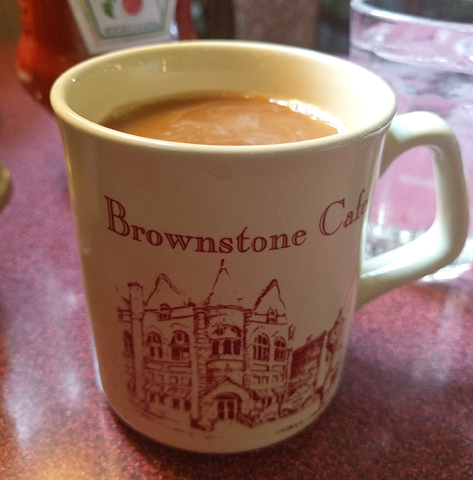 The official morning handshake at Brownstone Cafe&mdash;a sturdy mug of coffee featuring the building's historic facade. Caffeine with a side of architecture.